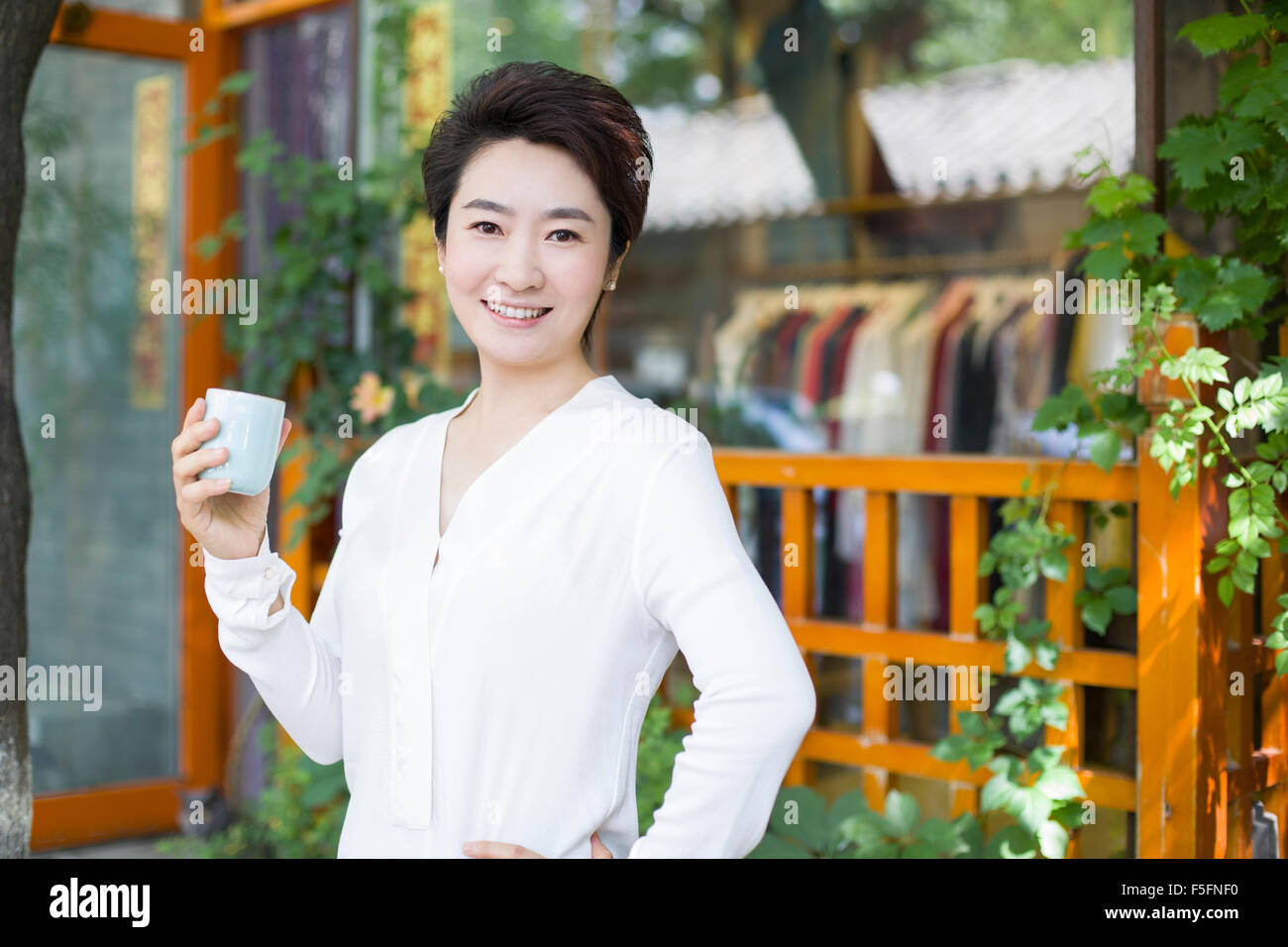 Female shopkeeper standing in doorway with a cup of tea Stock Photo - Alamy