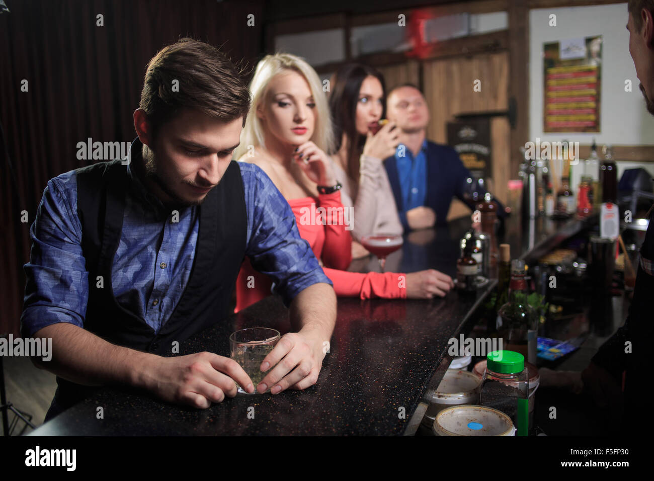 barman behind counter with young friends at cocktail bar Stock Photo ...