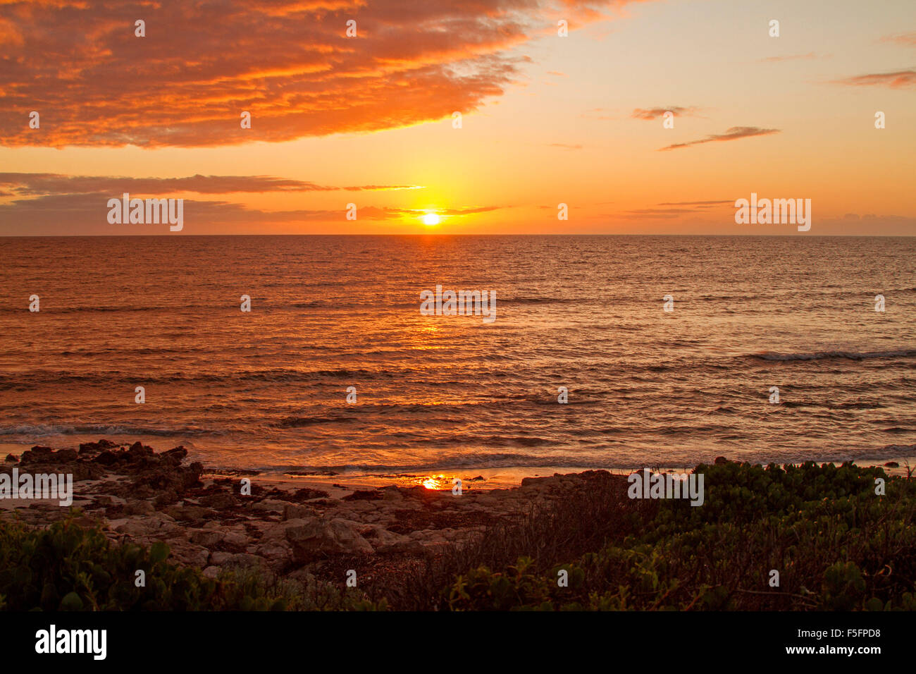 Spectacular colourful sunset with golden sky as sun sinks over ocean ...