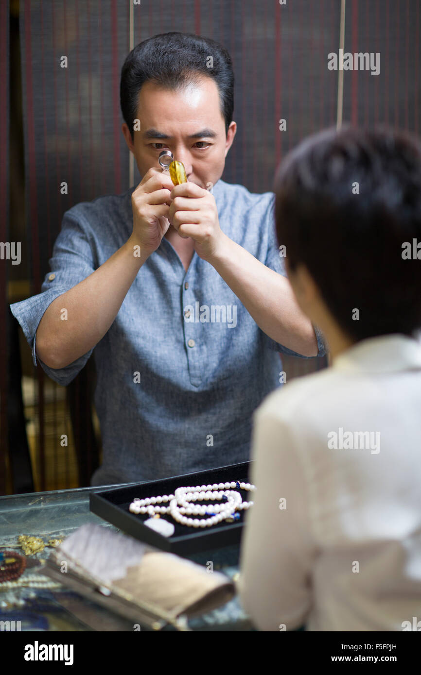 Male jeweler examining a jewelry Stock Photo - Alamy
