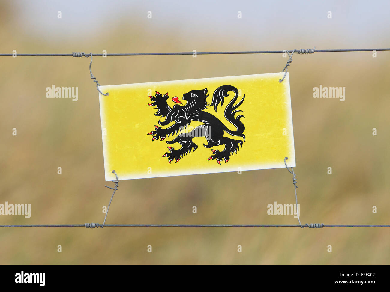 Border fence - Old plastic sign with a flag - Flanders Stock Photo - Alamy