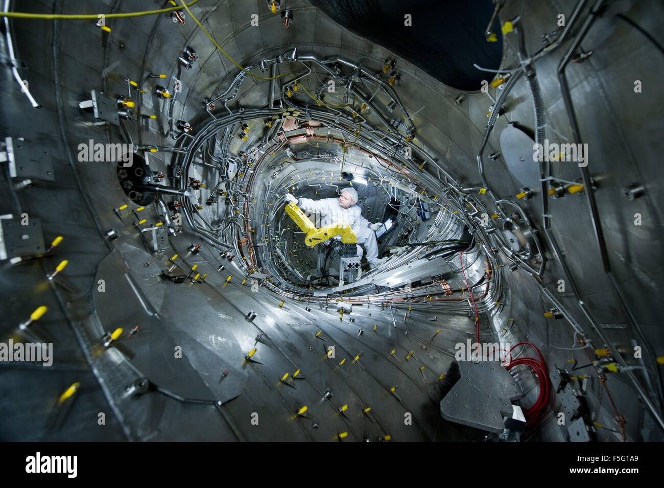 A man works on a circular plasma vessel at the research reactor ...