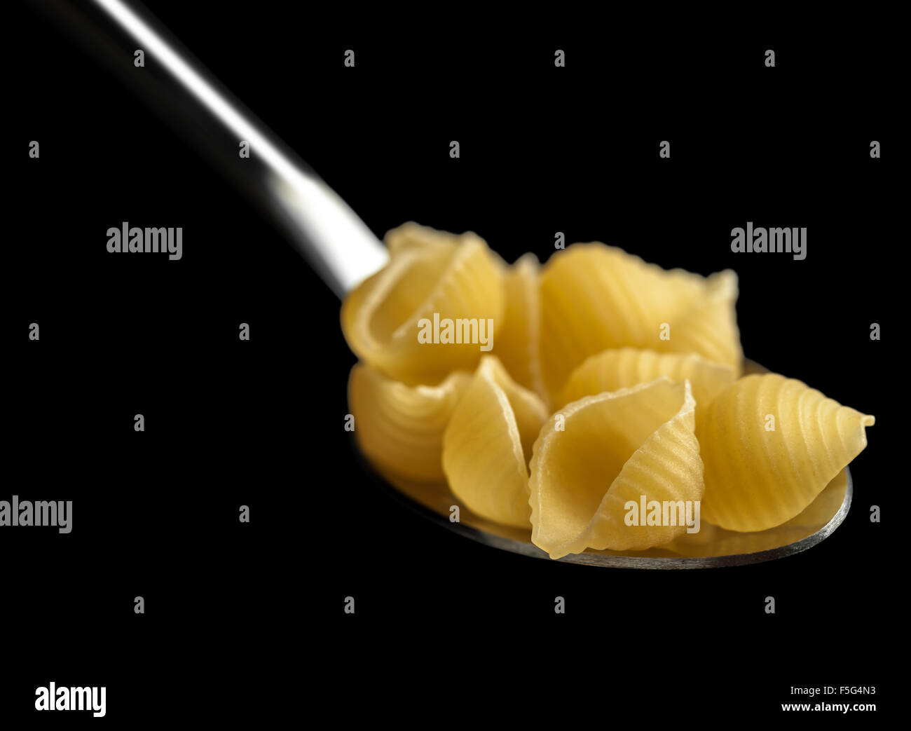 raw pasta in spoon closeup on a dark background Stock Photo - Alamy