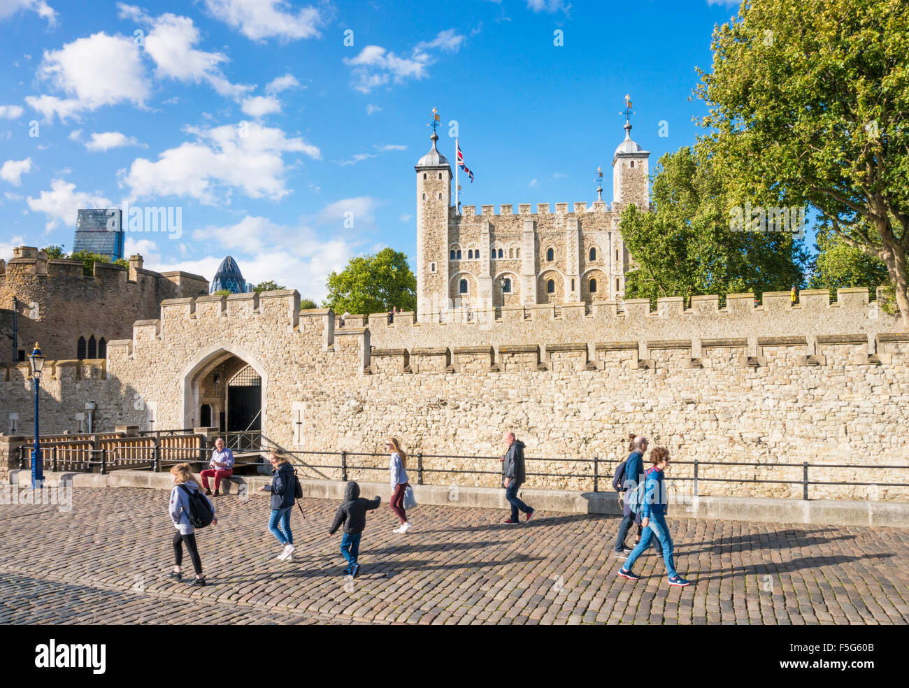 People walking past the castle walls and white tower Tower of London ...