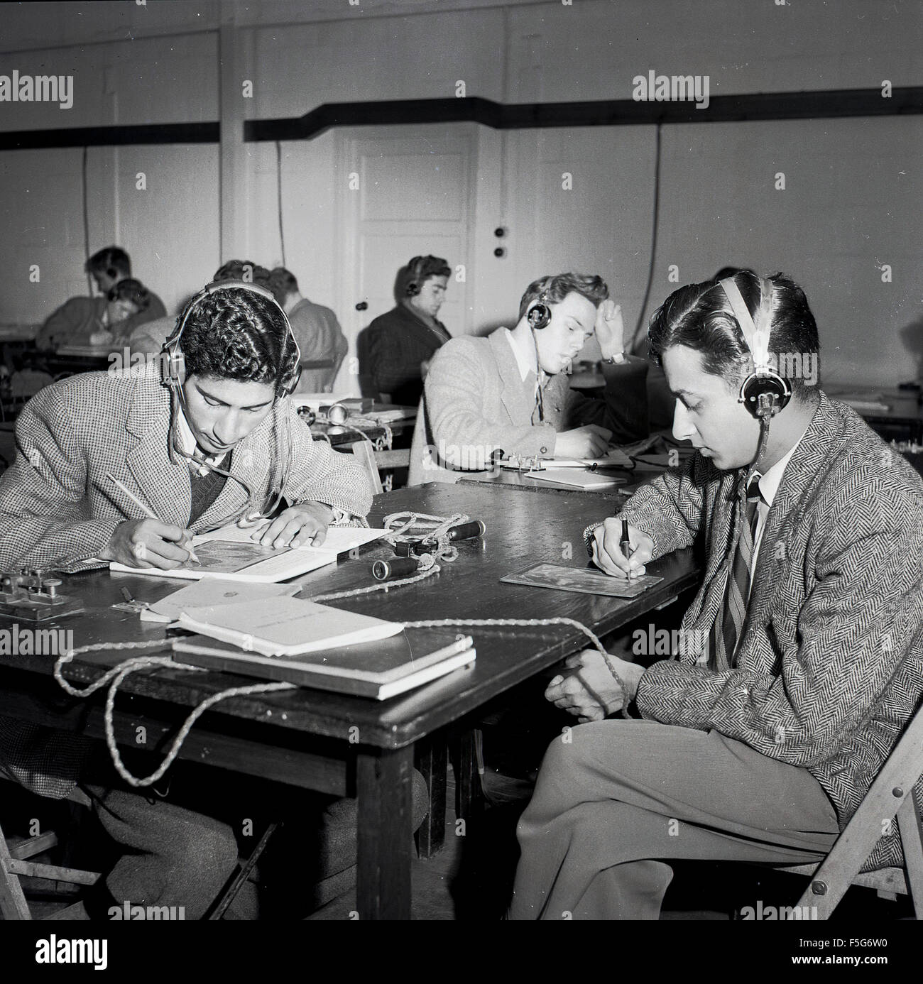 1950s historical, young male engineering apprentices at desks writing ...
