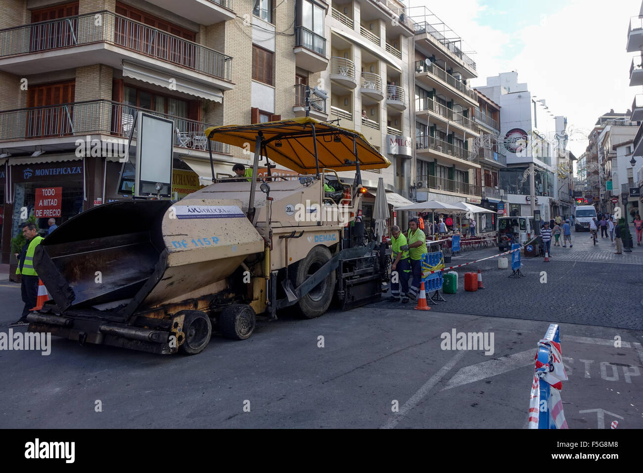 Spanish workmen prepare an artificial block paving surface using a grid ...