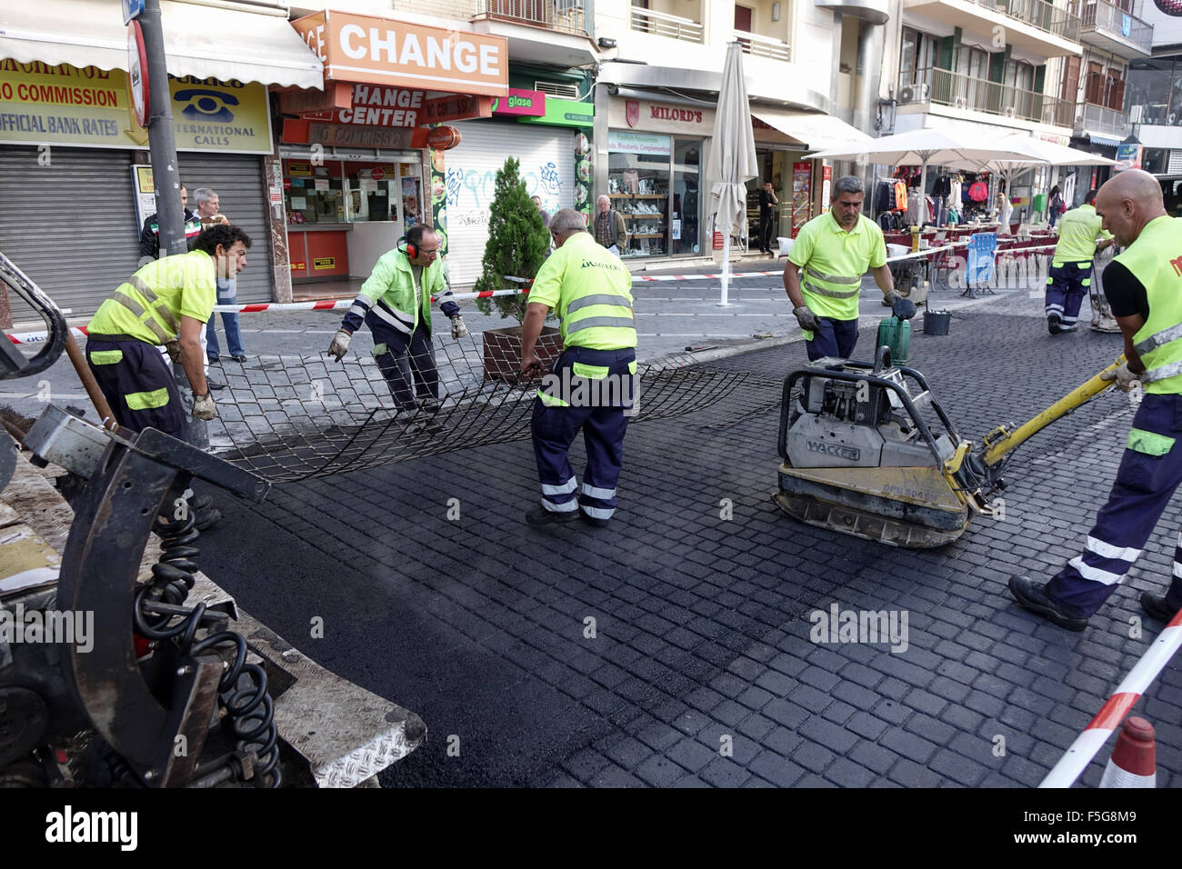 Spanish workmen prepare an artificial block paving surface using a grid ...