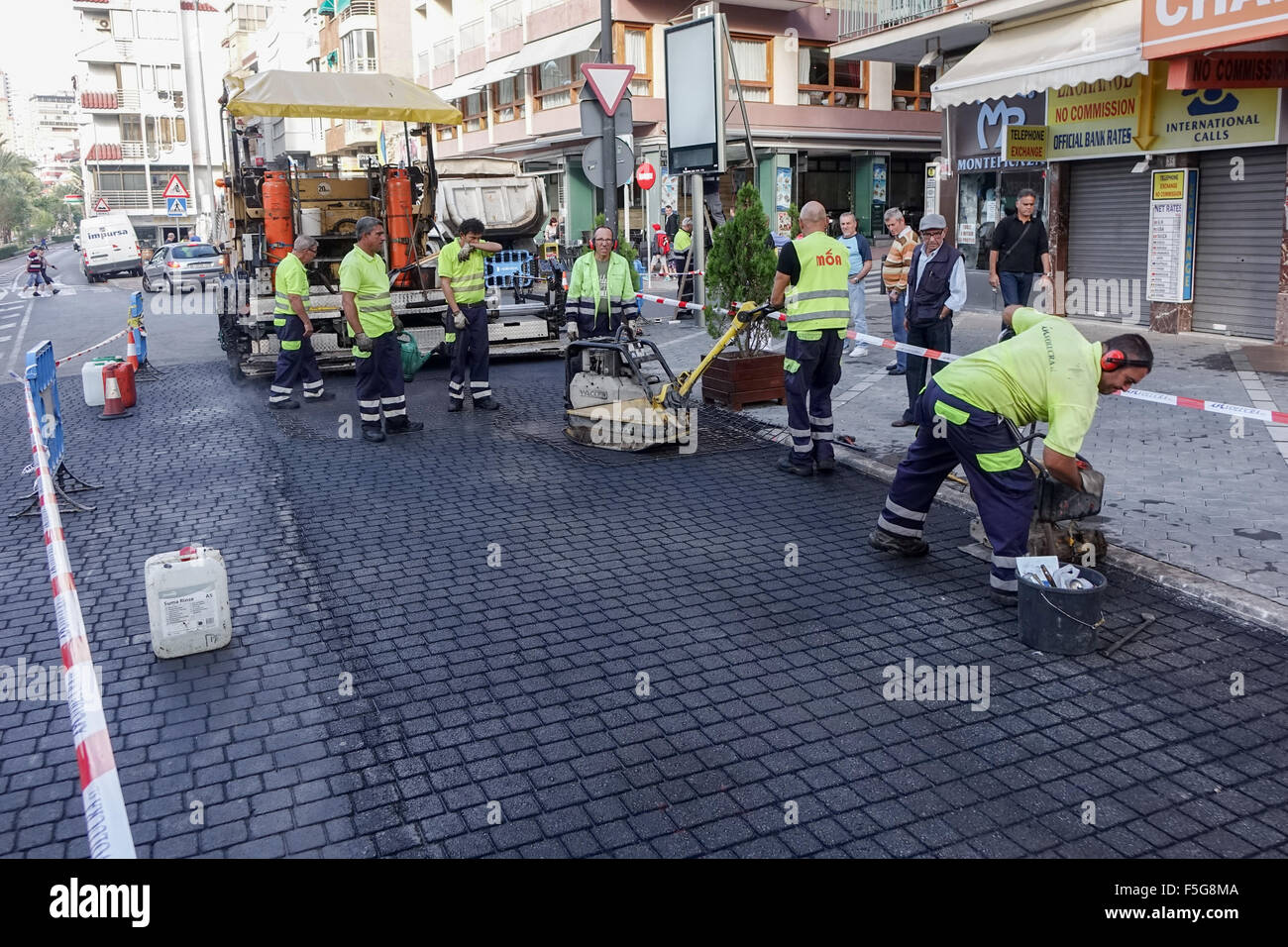 Spanish workmen prepare an artificial block paving surface using a grid ...