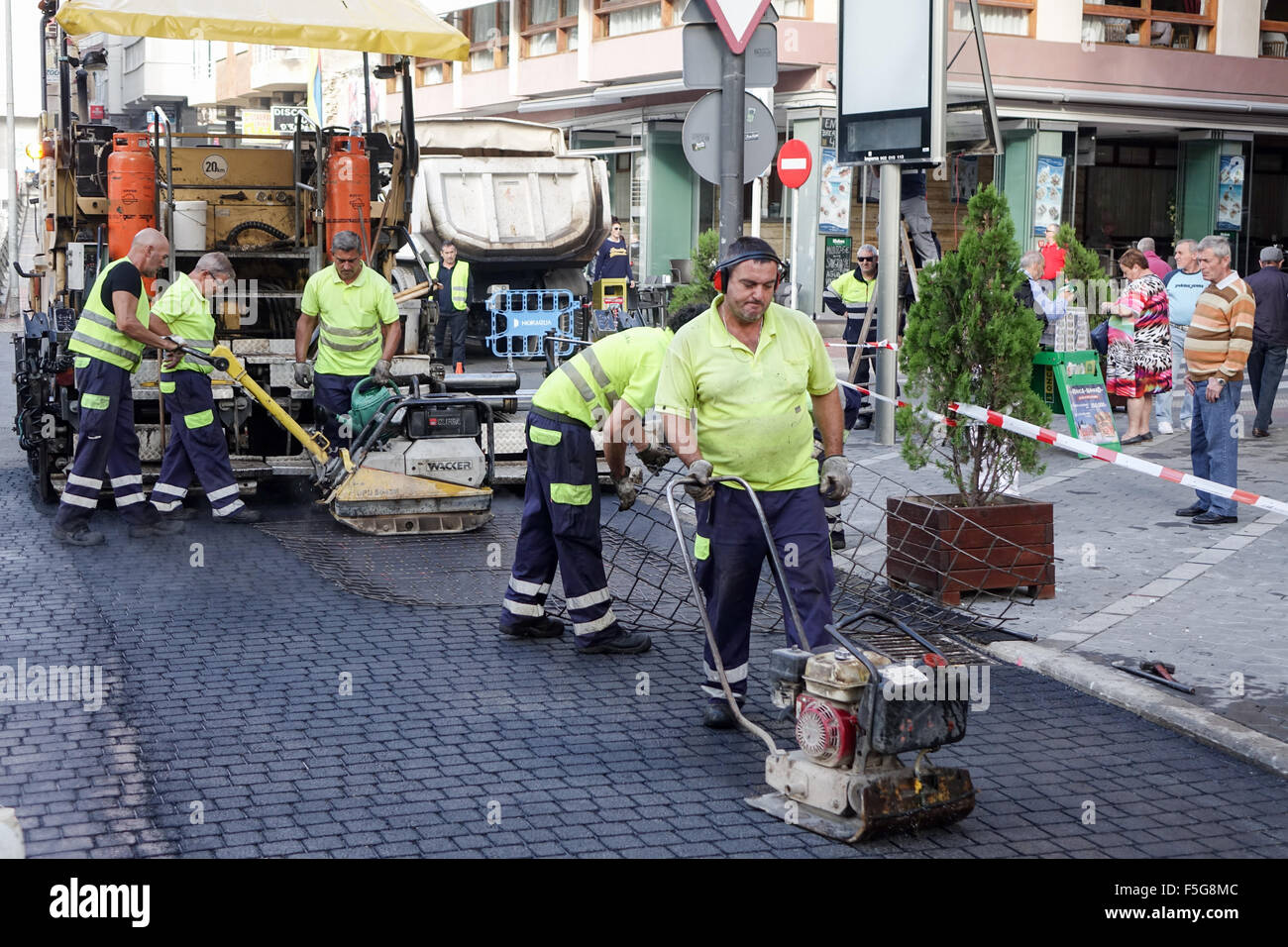 Spanish workmen prepare an artificial block paving surface using a grid ...