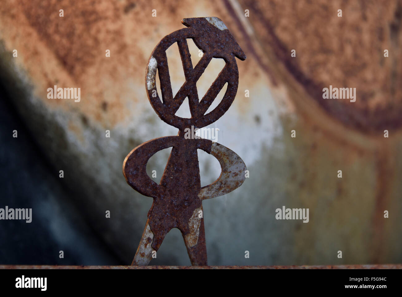 A rusty Volkswagen man stands on the bumper of a VW Beetle in the ...