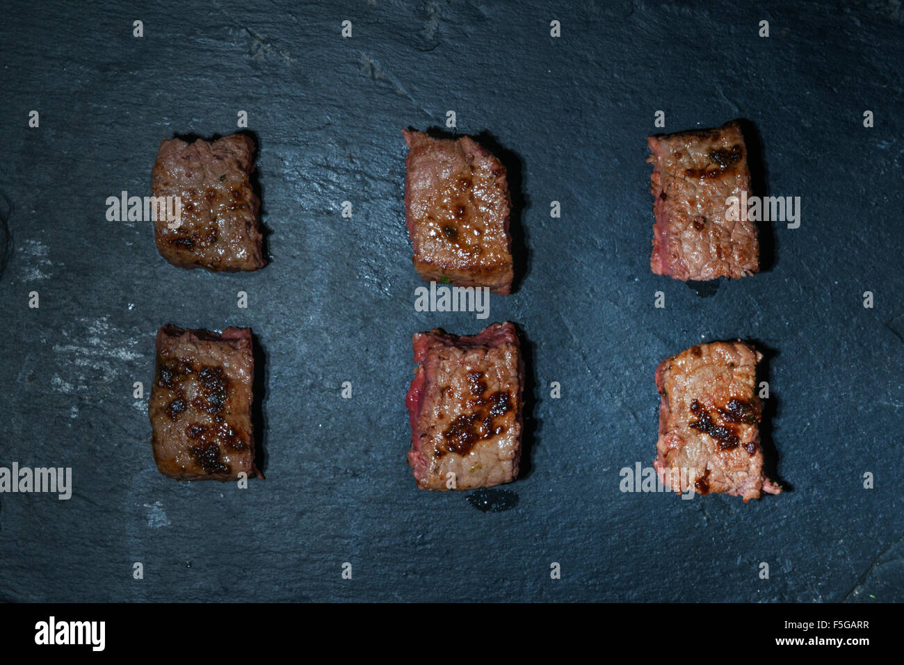 six pieces of steak layout out in order on a granite slate Stock Photo ...