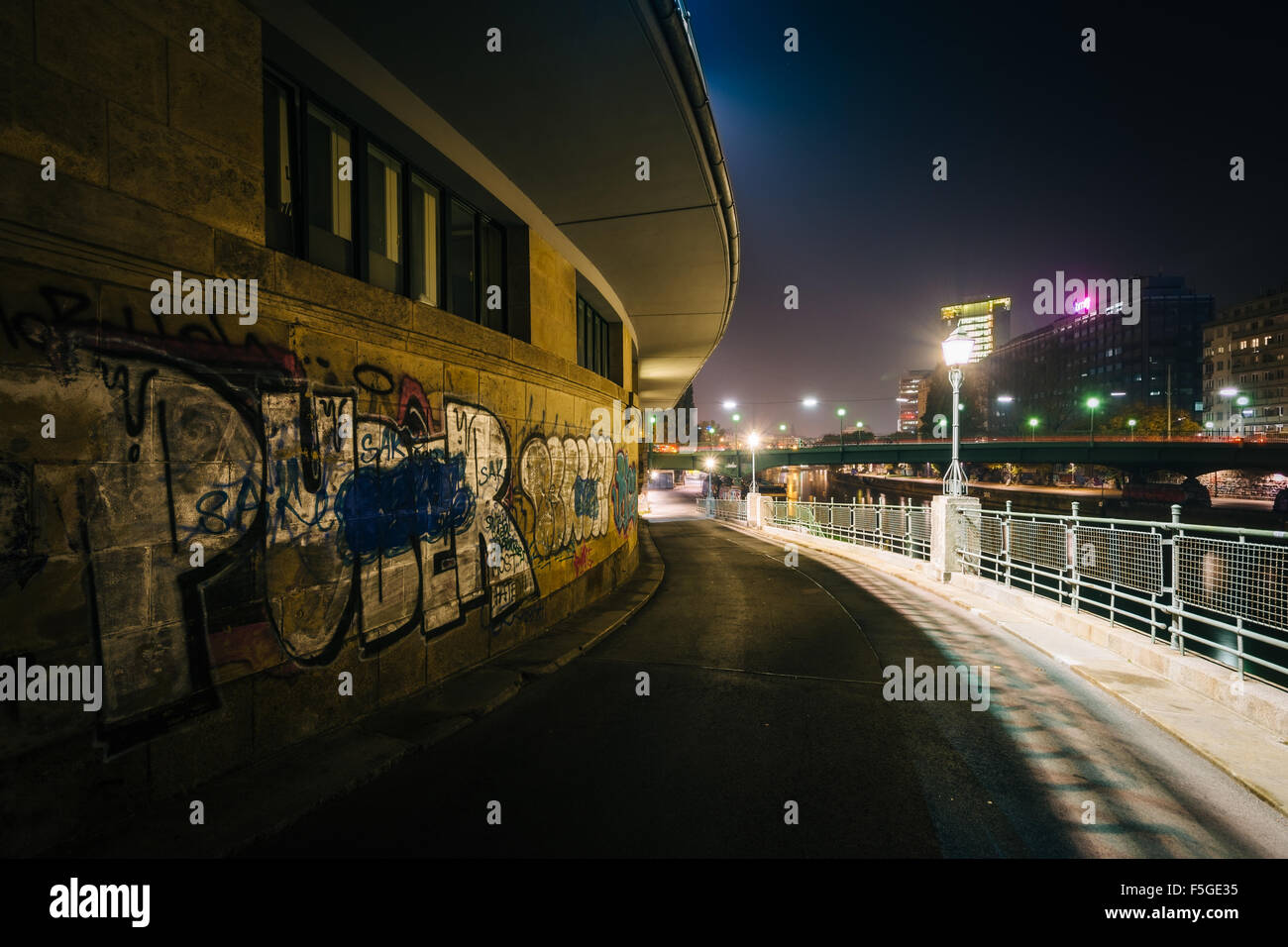 Graffiti on a wall along the Danube Canal at night, in Vienna, Austria ...