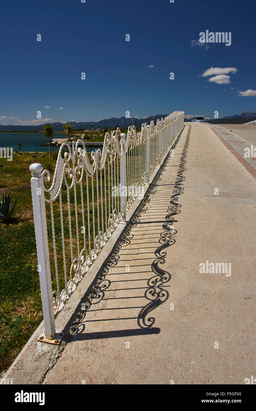 Road and pedestrian bridge with decorative white railings and shadows ...