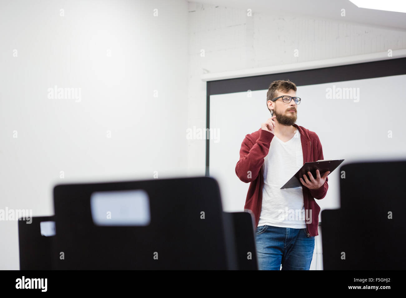 Young teacher in glasses with beard standing near the whiteboard in ...