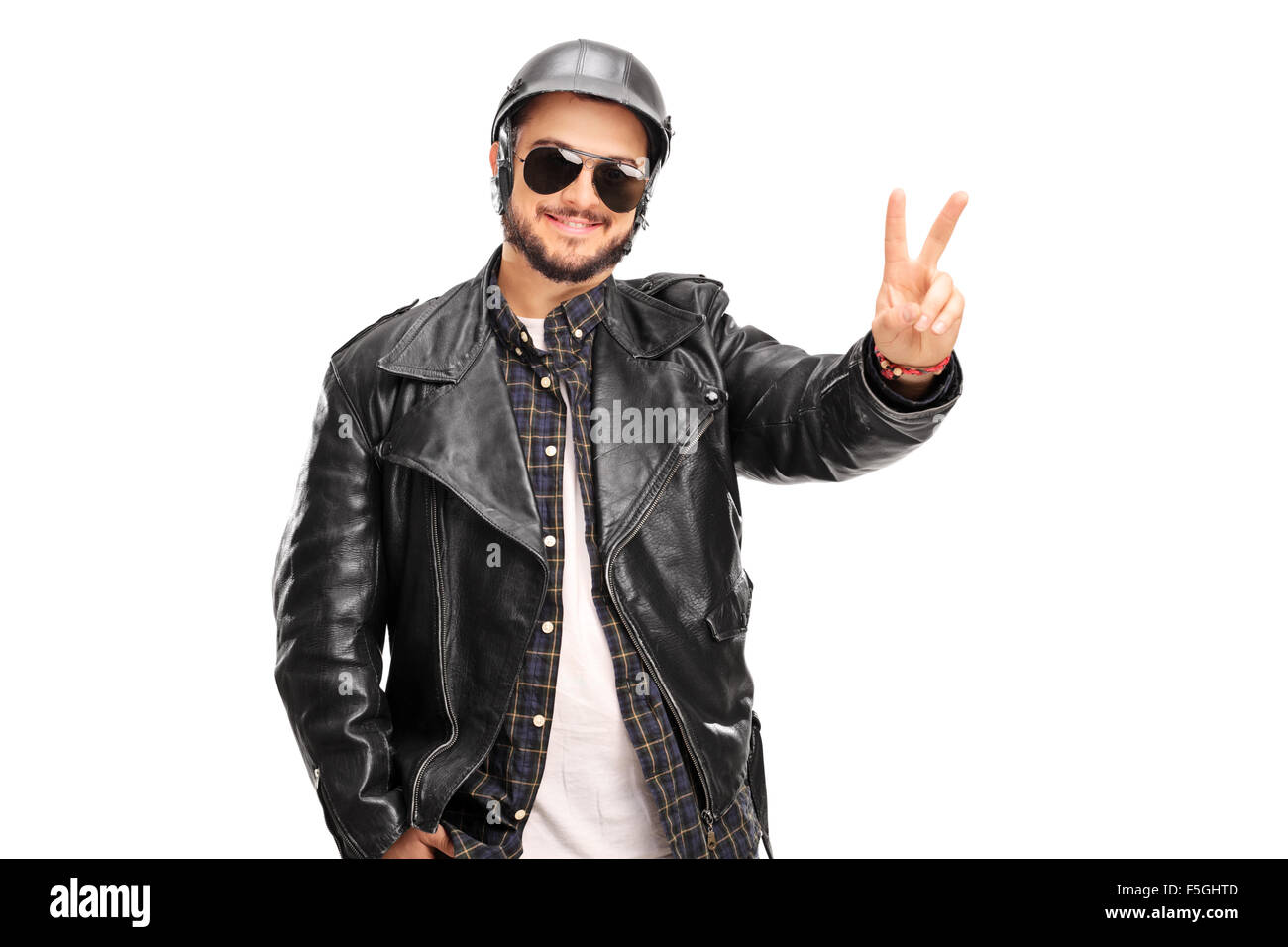 Young cheerful biker in a black leather jacket making a peace hand ...