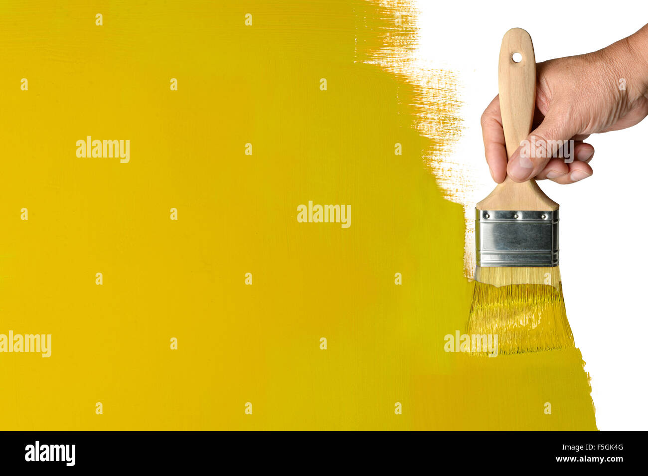 Man's hand using paintbrush with yellow paint on wall Stock Photo - Alamy
