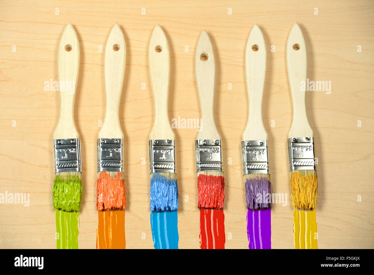 Six paintbrushes with paint of different colors over wood Stock Photo ...