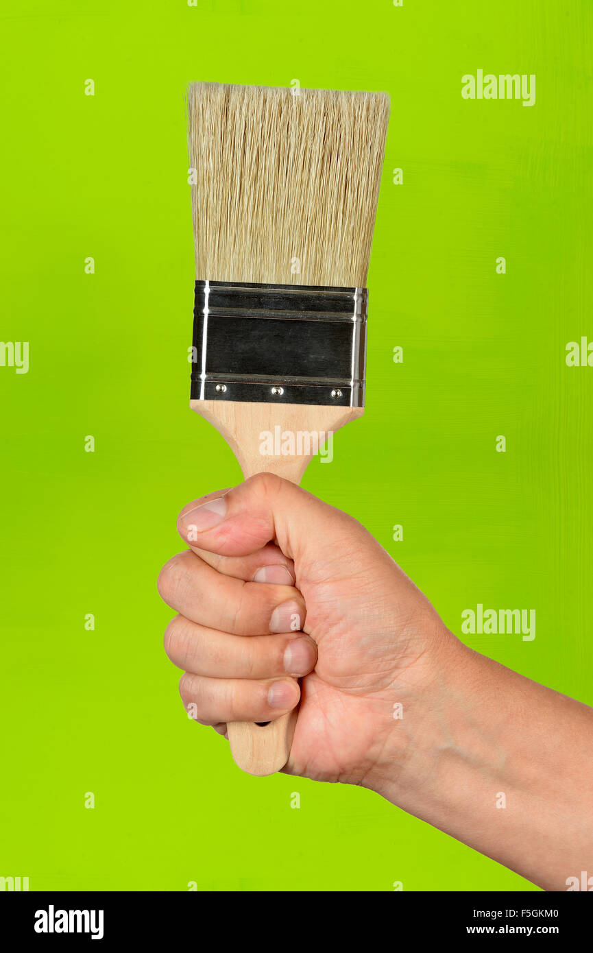 Hand holding paintbrush over green painted wall Stock Photo - Alamy