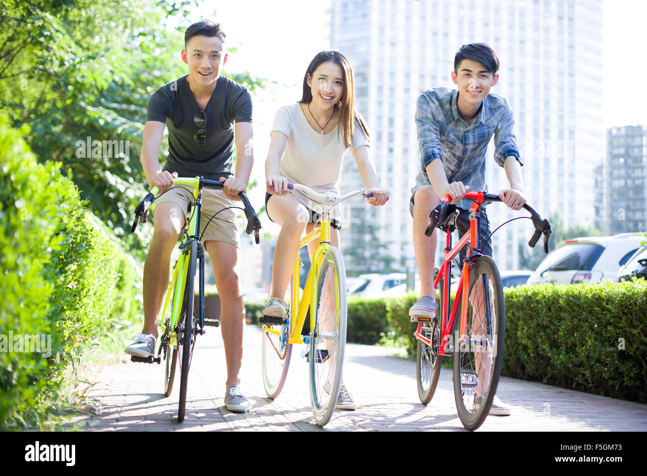 Happy young adults riding bicycles Stock Photo - Alamy