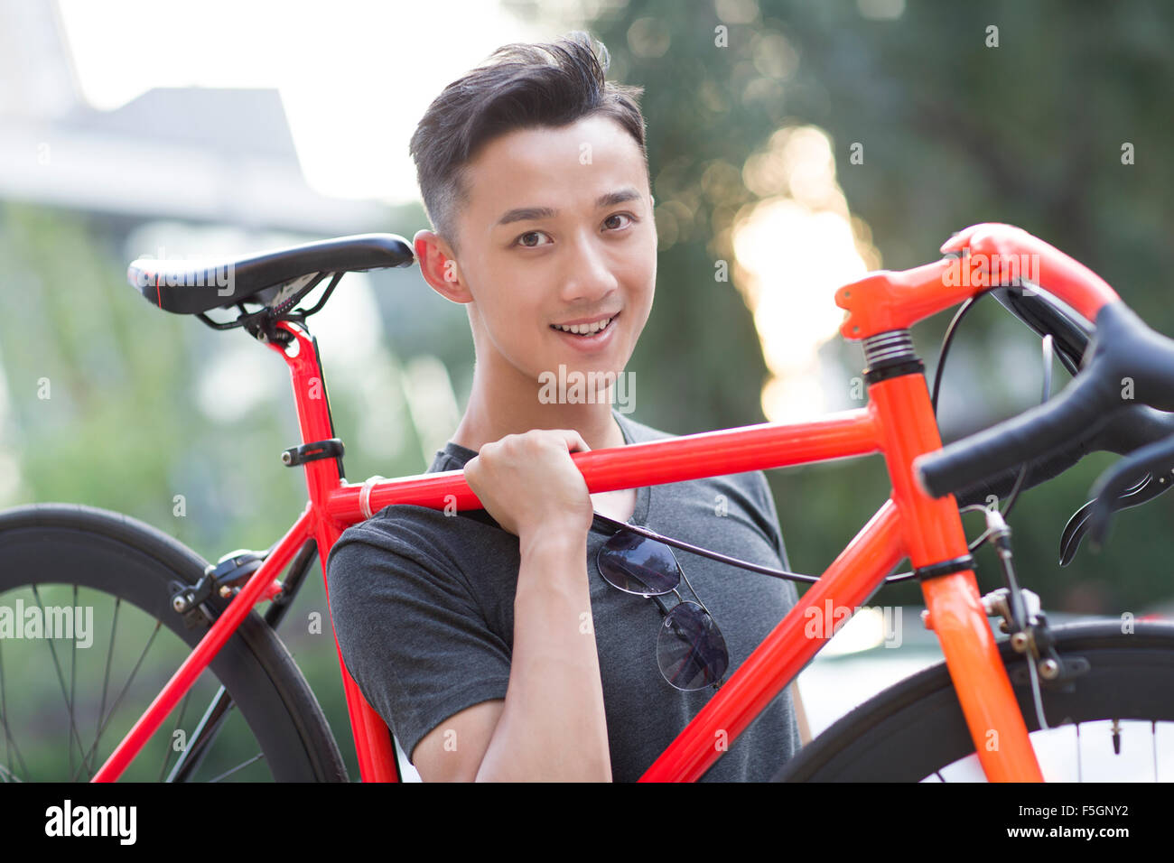 Young man carrying bicycle on shoulder Stock Photo - Alamy