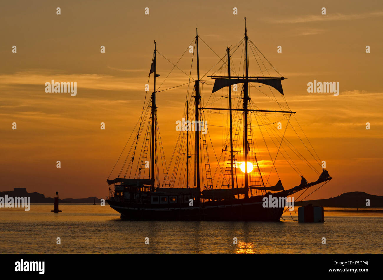 sunset silhouetted tall ship at anchor with setting sun Stock Photo - Alamy