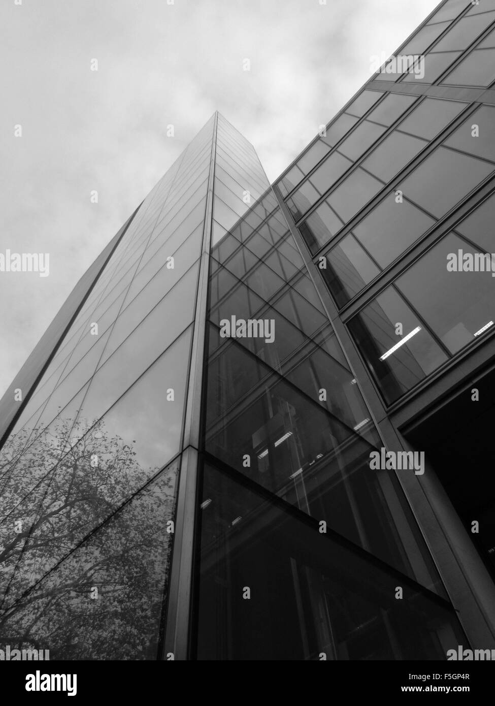 Photograph of a glass building reflecting another building with a three ...