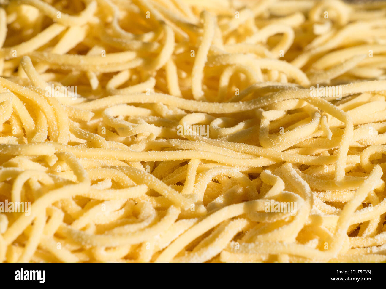 Extreme close up detail of home made spaghetti, with flour on surface ...