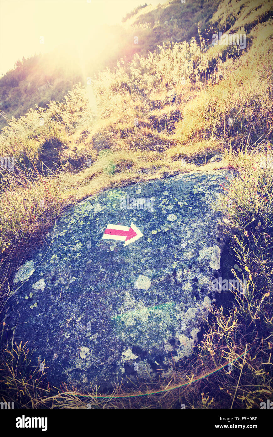 Retro stylized trail arrow sign against sunset with lens flare effect ...