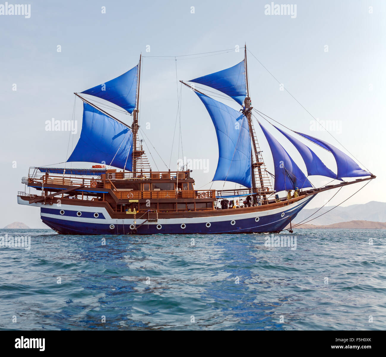 Vintage Wooden Ship with Blue Sails near Komodo Island, Indonesia Stock ...