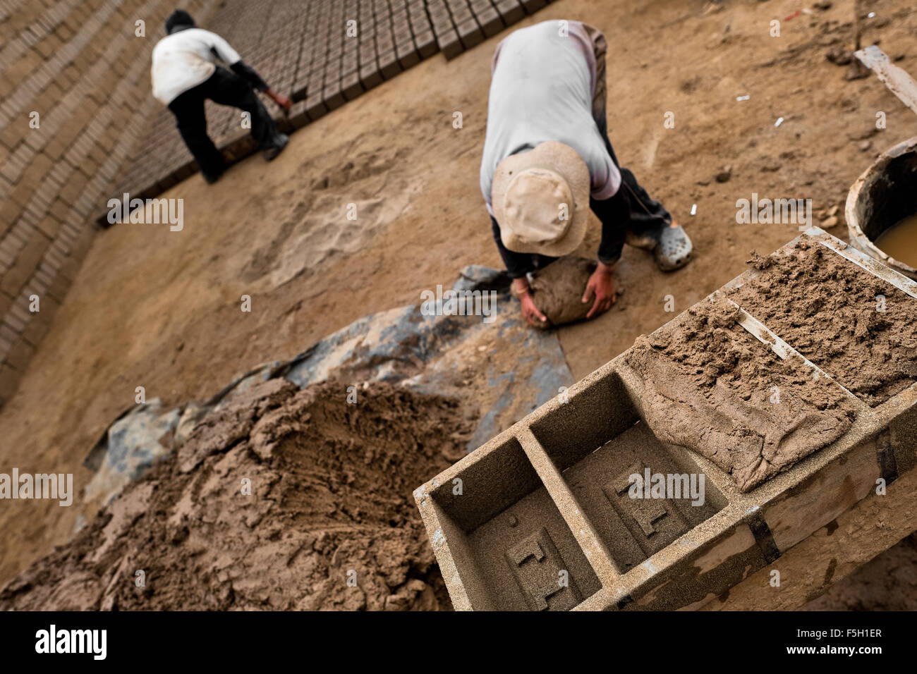 A Peruvian boy carries raw clay for brick making at a brick factory in ...