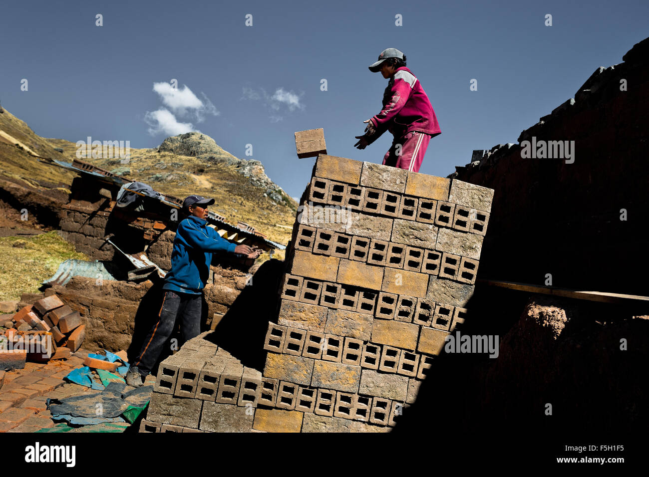 Peruvian boys pile raw bricks aside a kiln at a brick factory in the ...