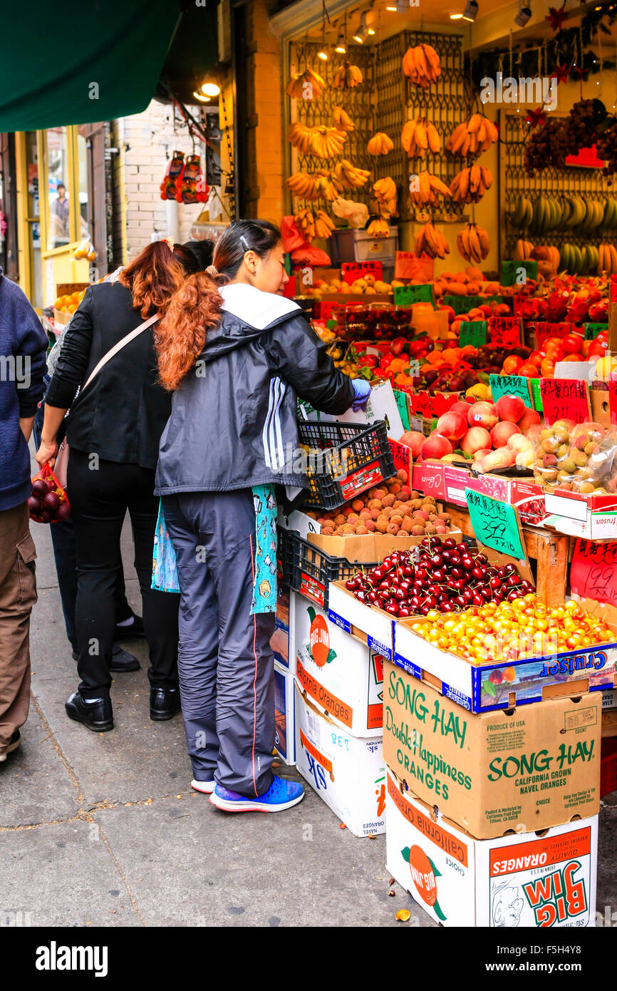 Chinese woman adds to the store display of fresh fruit and veg in ...