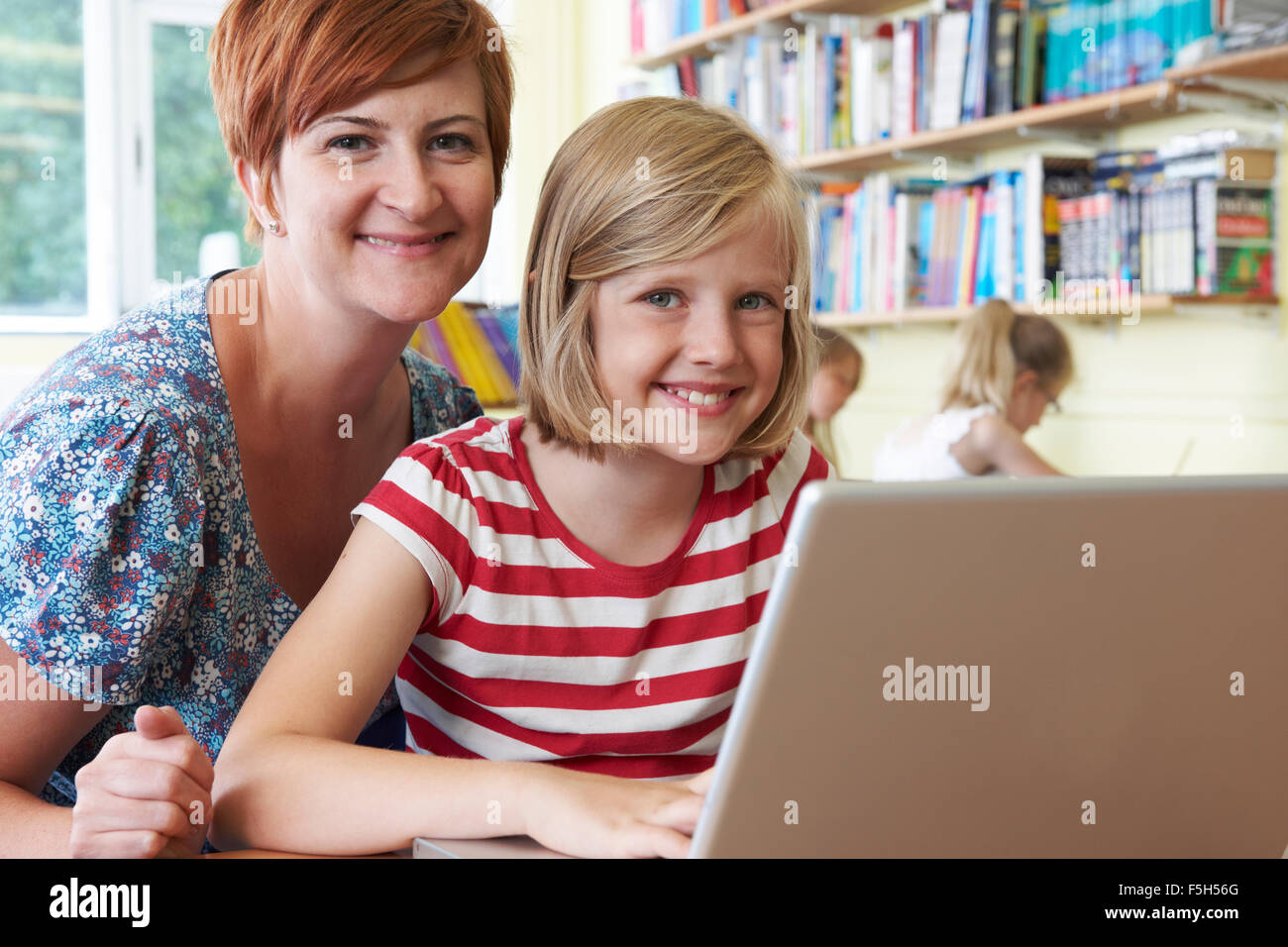 School Pupil With Teacher Using Laptop Computer In Classroom Stock ...