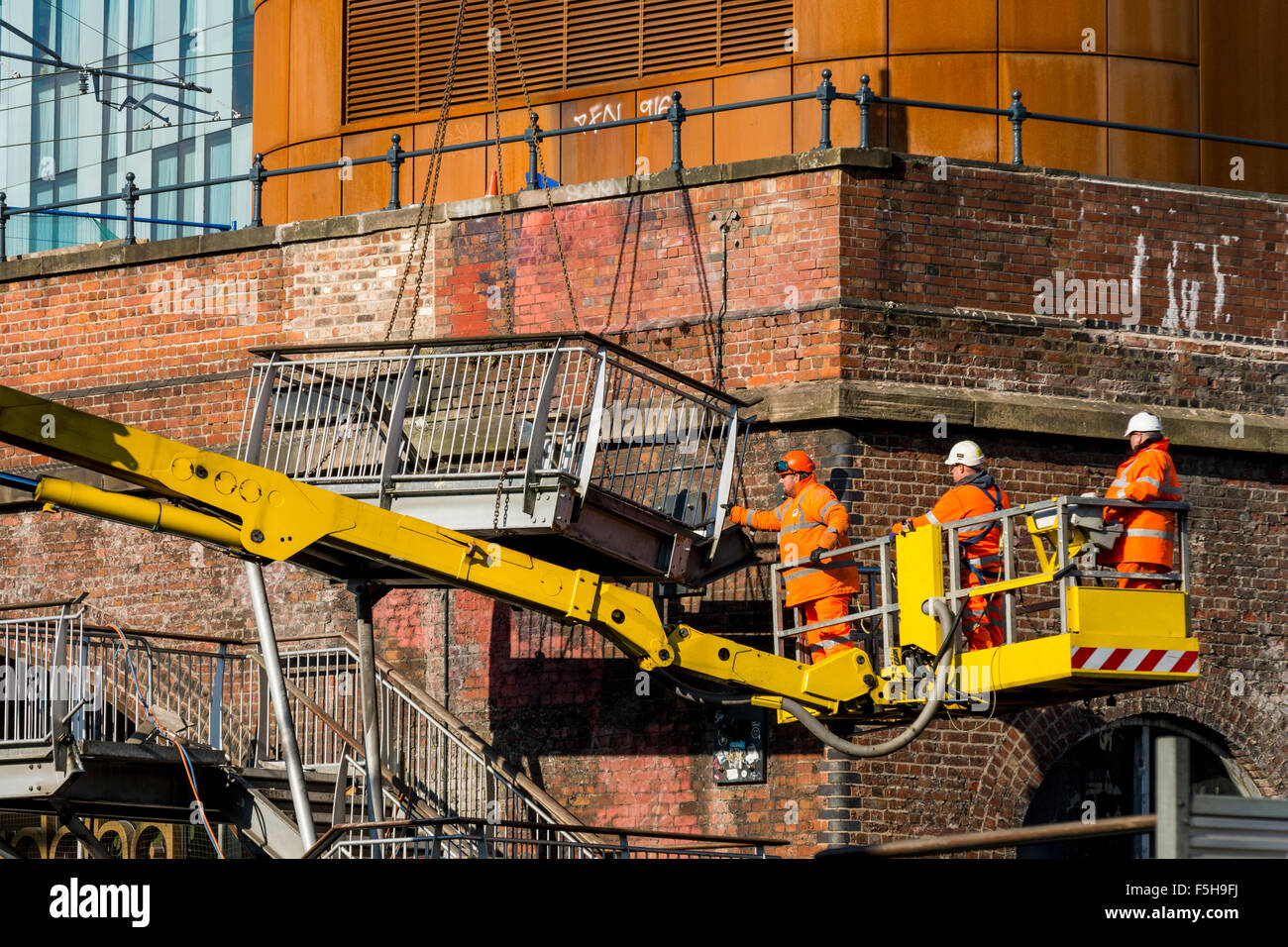 Workman on an access platform dismantling an old staircase at the ...