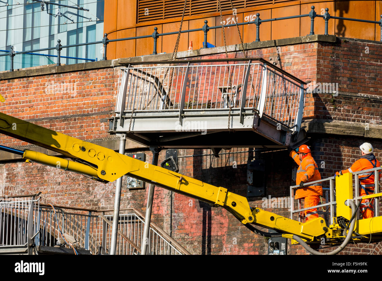 Workman on an access platform dismantling an old staircase at the ...