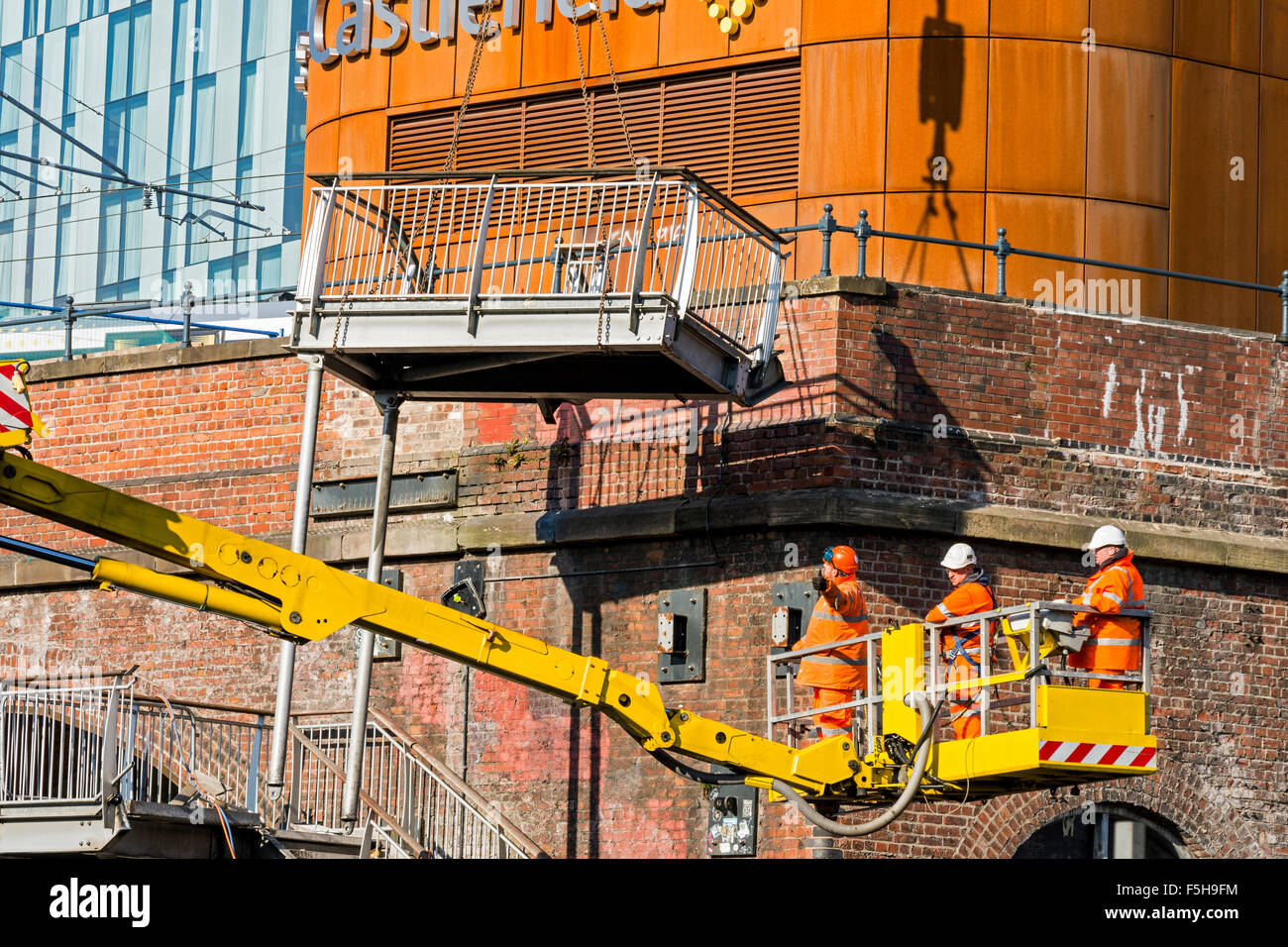 Workman on an access platform dismantling an old staircase at the ...