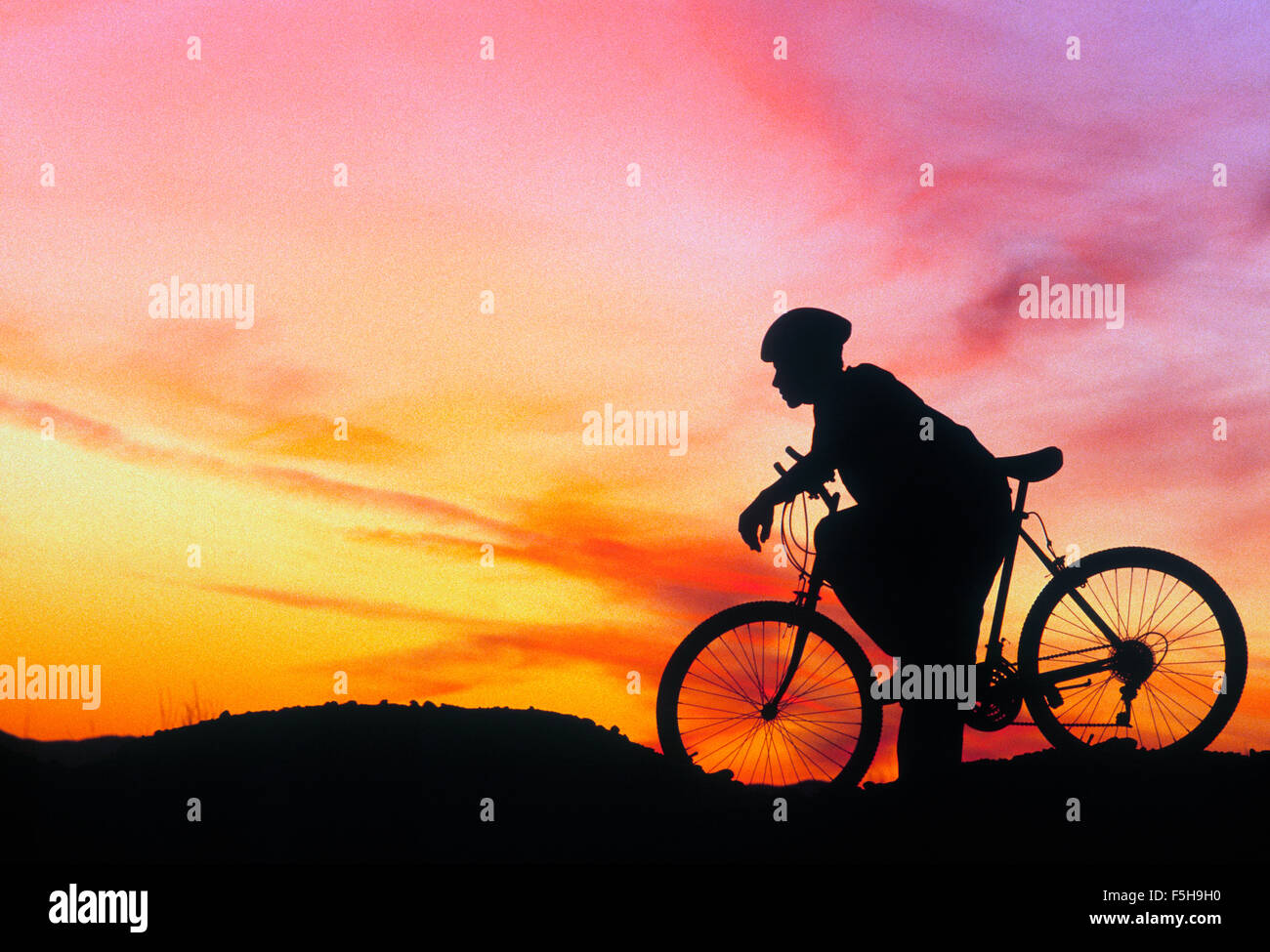 cyclist resting on hilltop at sunset Stock Photo - Alamy