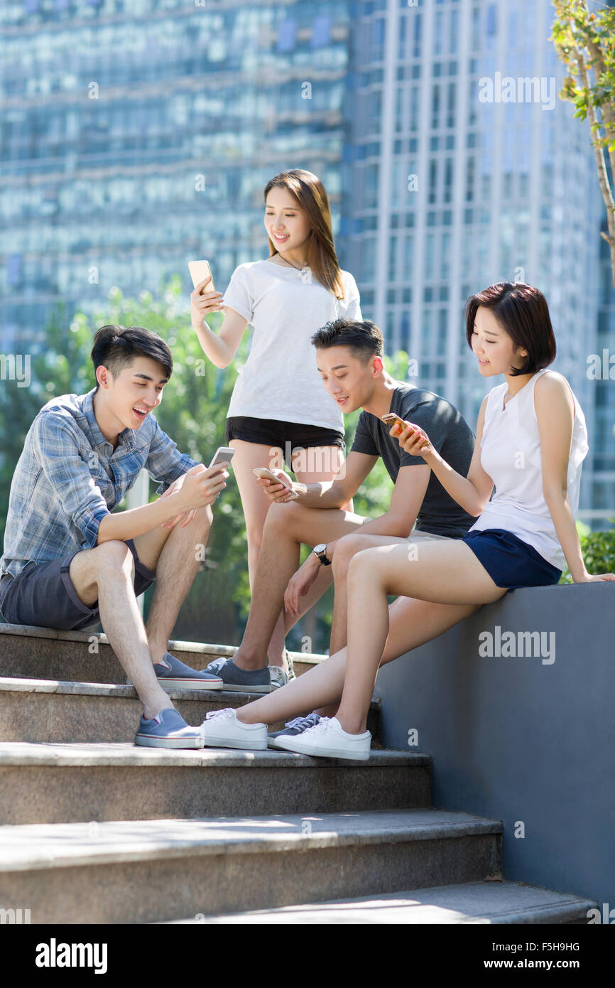 Happy young adults using smart phone together Stock Photo - Alamy