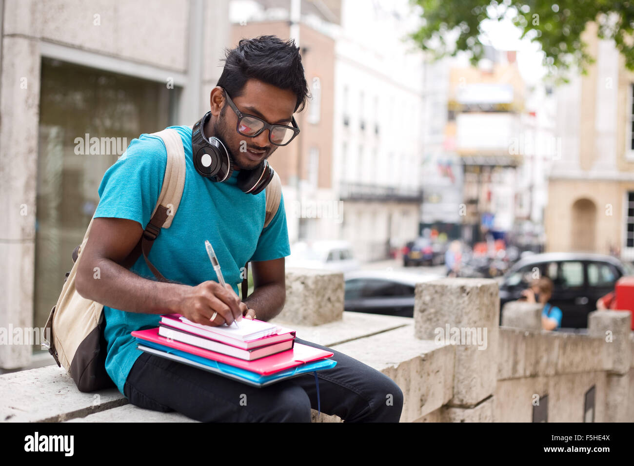 student sitting outdoors writing in a textbook Stock Photo - Alamy