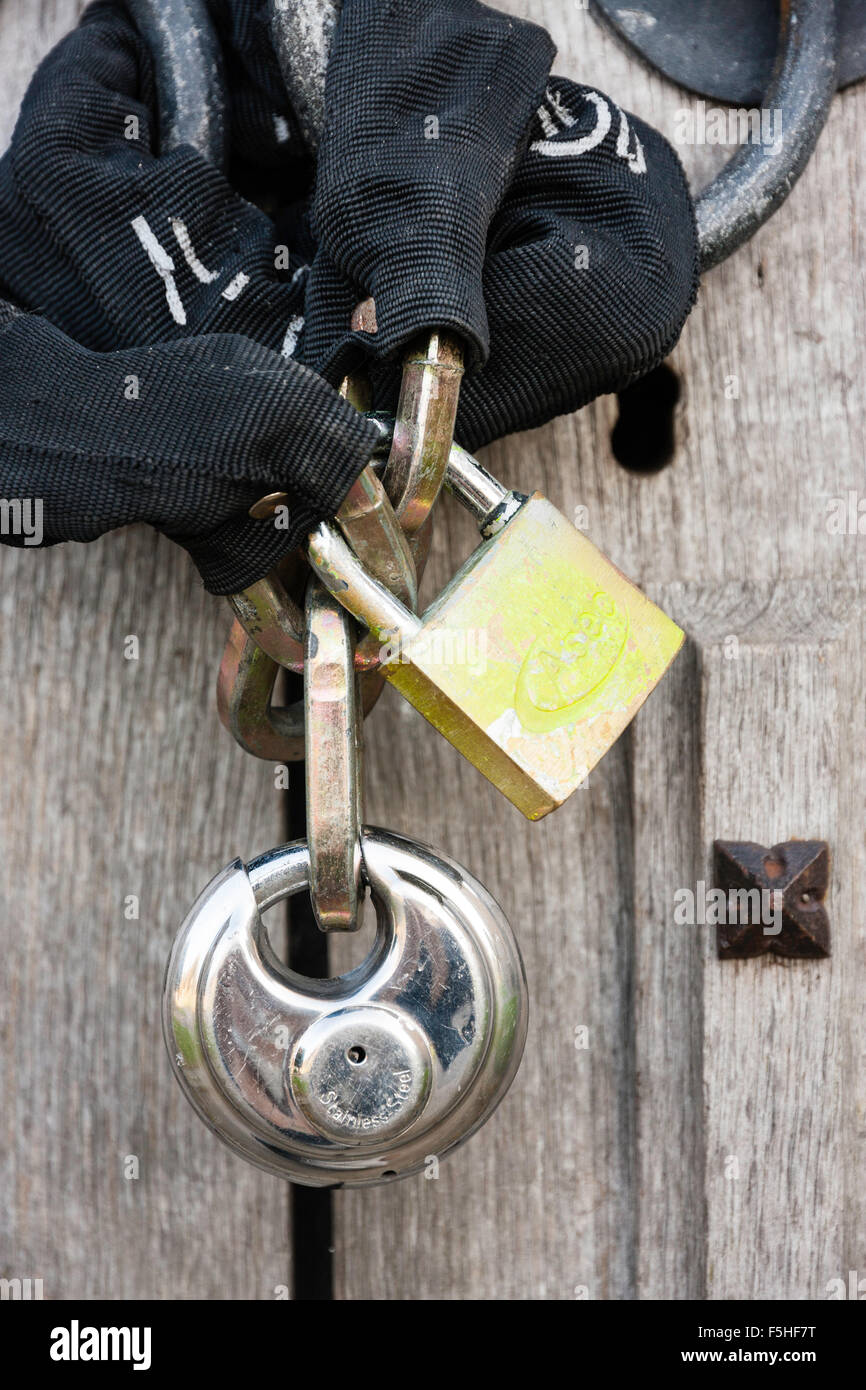 Close up of double padlocked chain connected to two open door handle ...