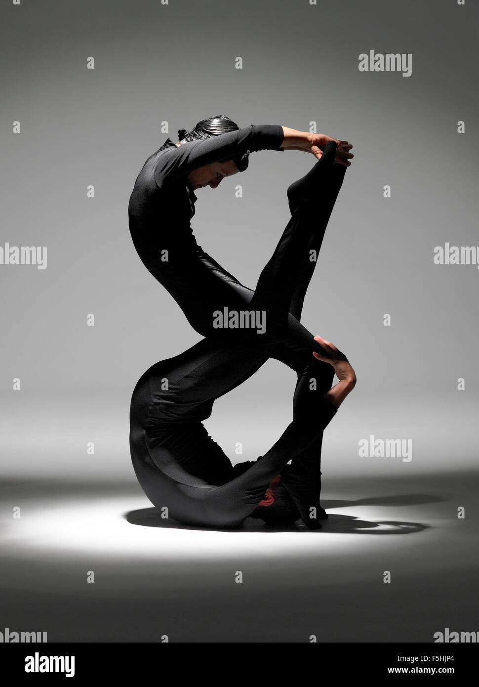 Couple of contortionist bending 8 number against grey background ...