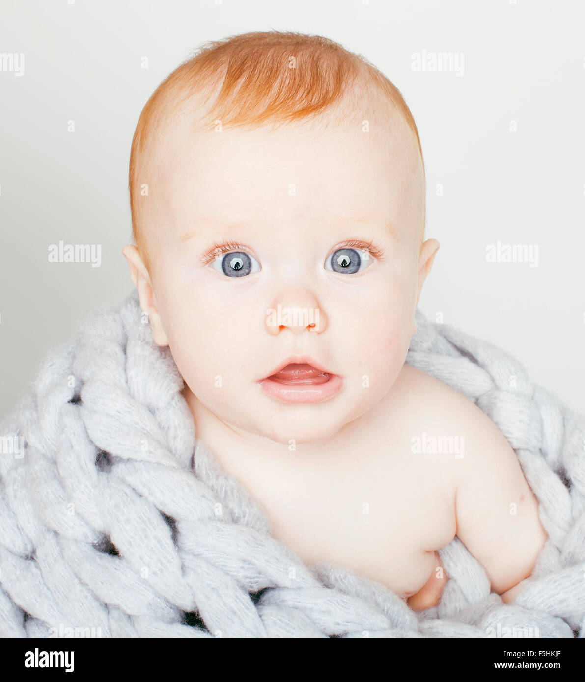 little cute red head baby in scarf all over him close up isolated ...