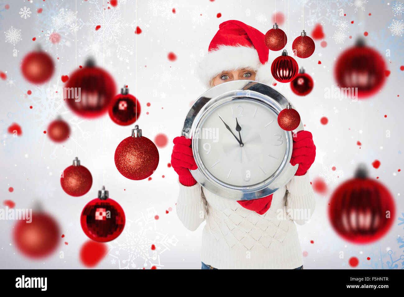 Composite image of festive woman holding clock Stock Photo - Alamy