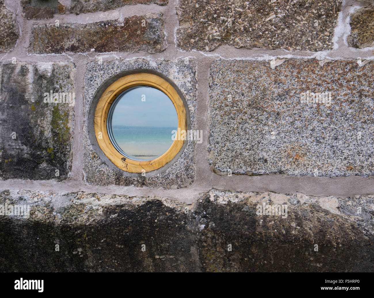 Seaside circular porthole embedded in weathered stone wall Stock Photo ...