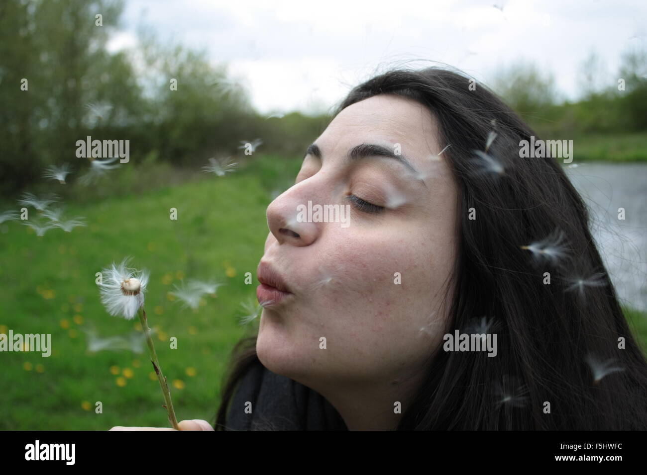 Greek woman blowing a dandelion into the wind Stock Photo - Alamy
