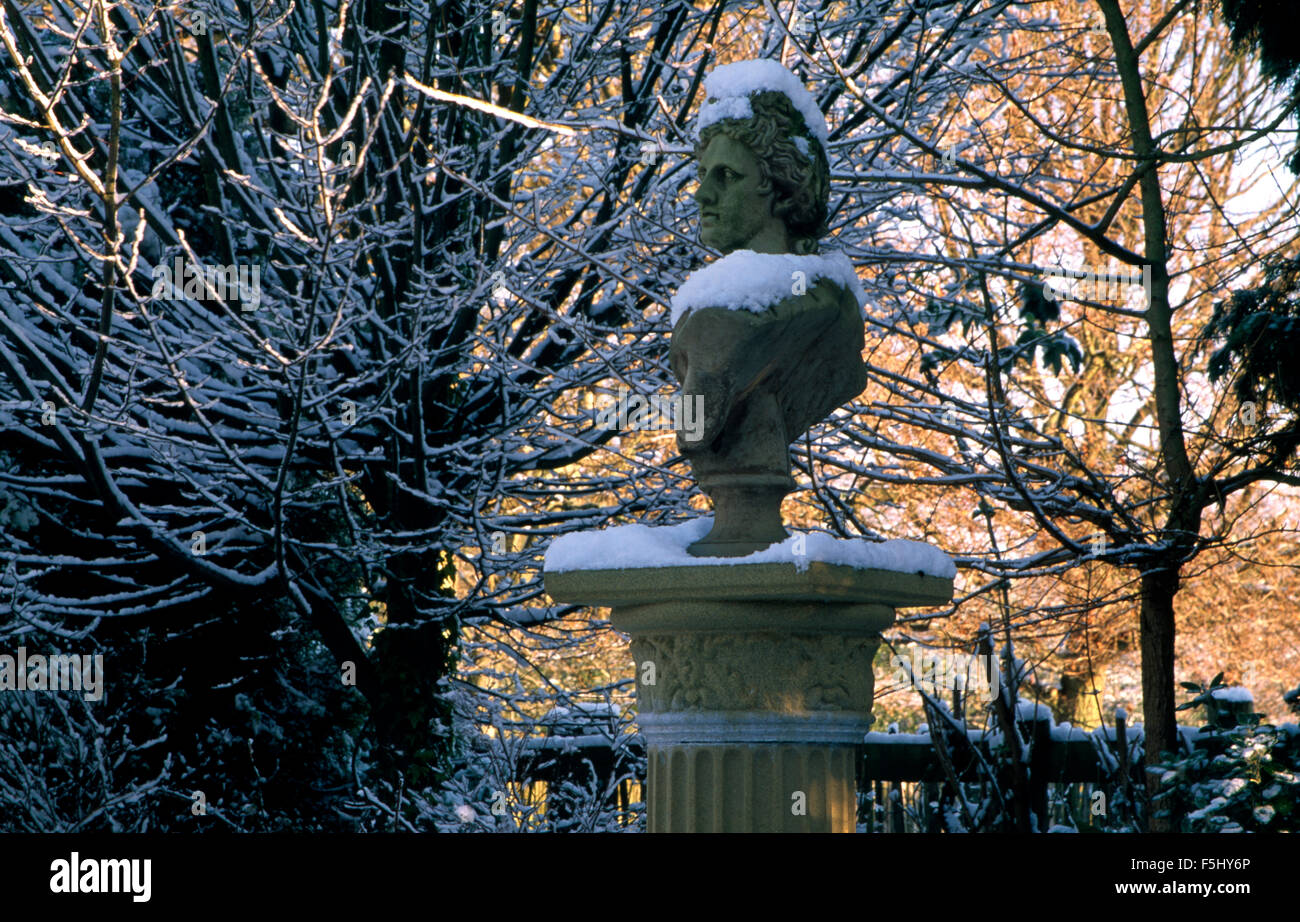 Snow covered stone statue in winter garden Stock Photo - Alamy