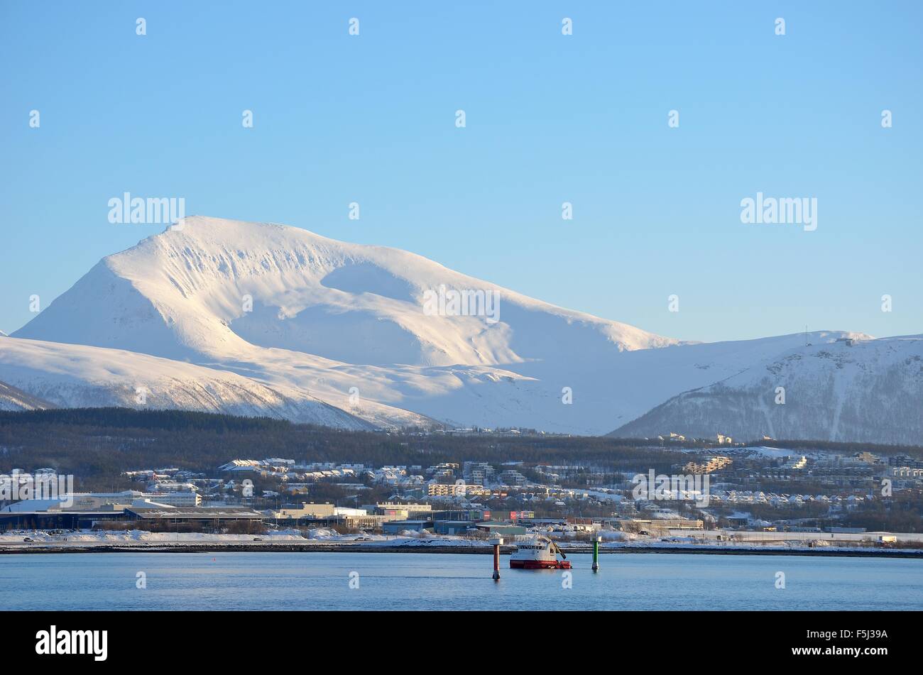 ship in sea in front of the city island of tromso with snowy mountain ...