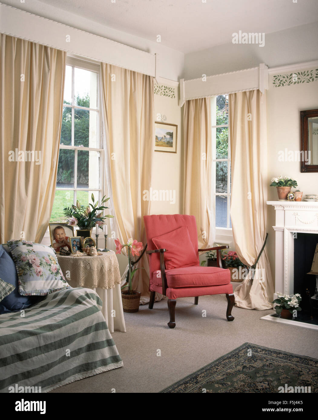 Pink chair between windows with cream curtains in nineties living room ...