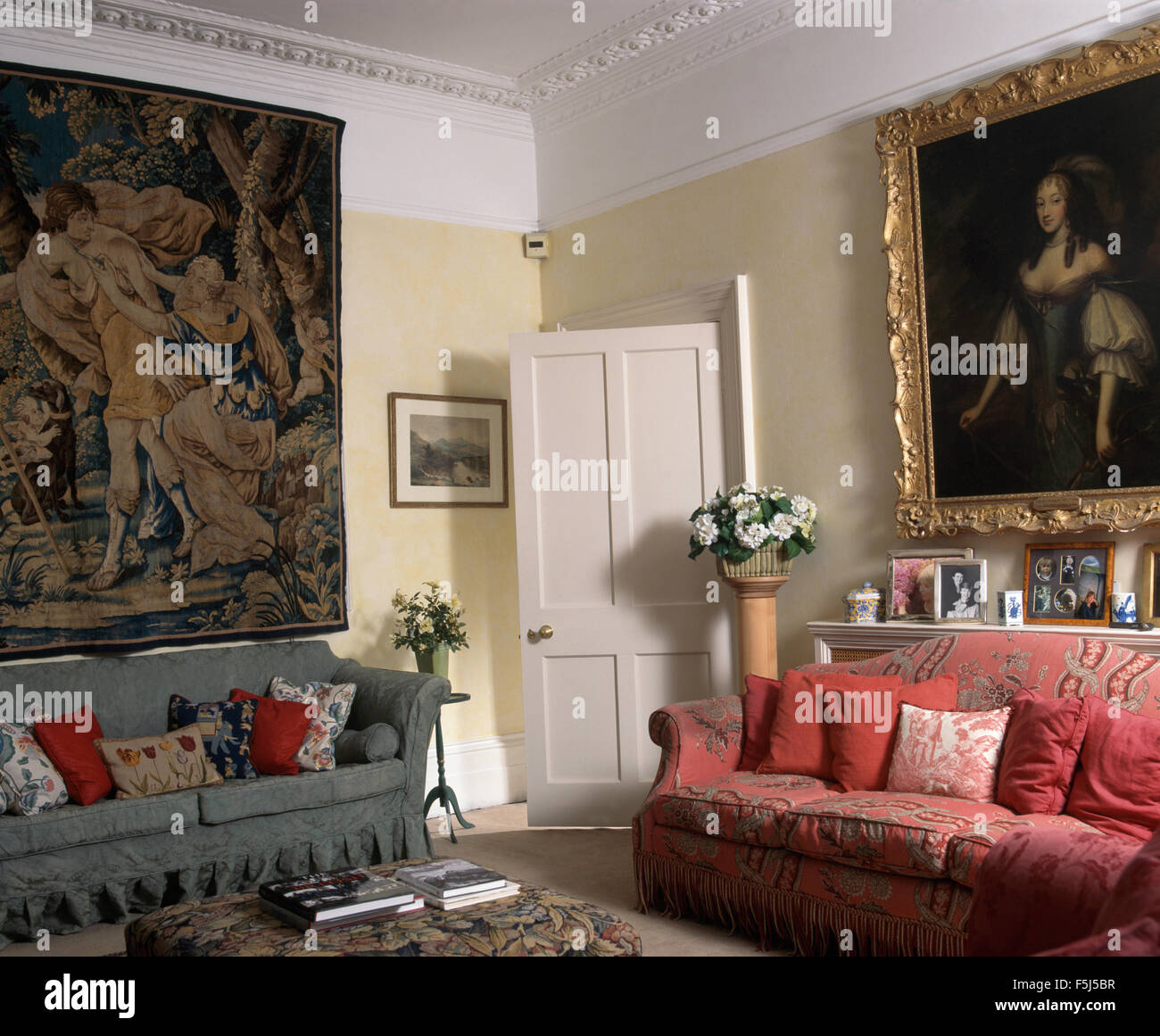 Large tapestry and an oil portrait above gray and red sofas in a ...