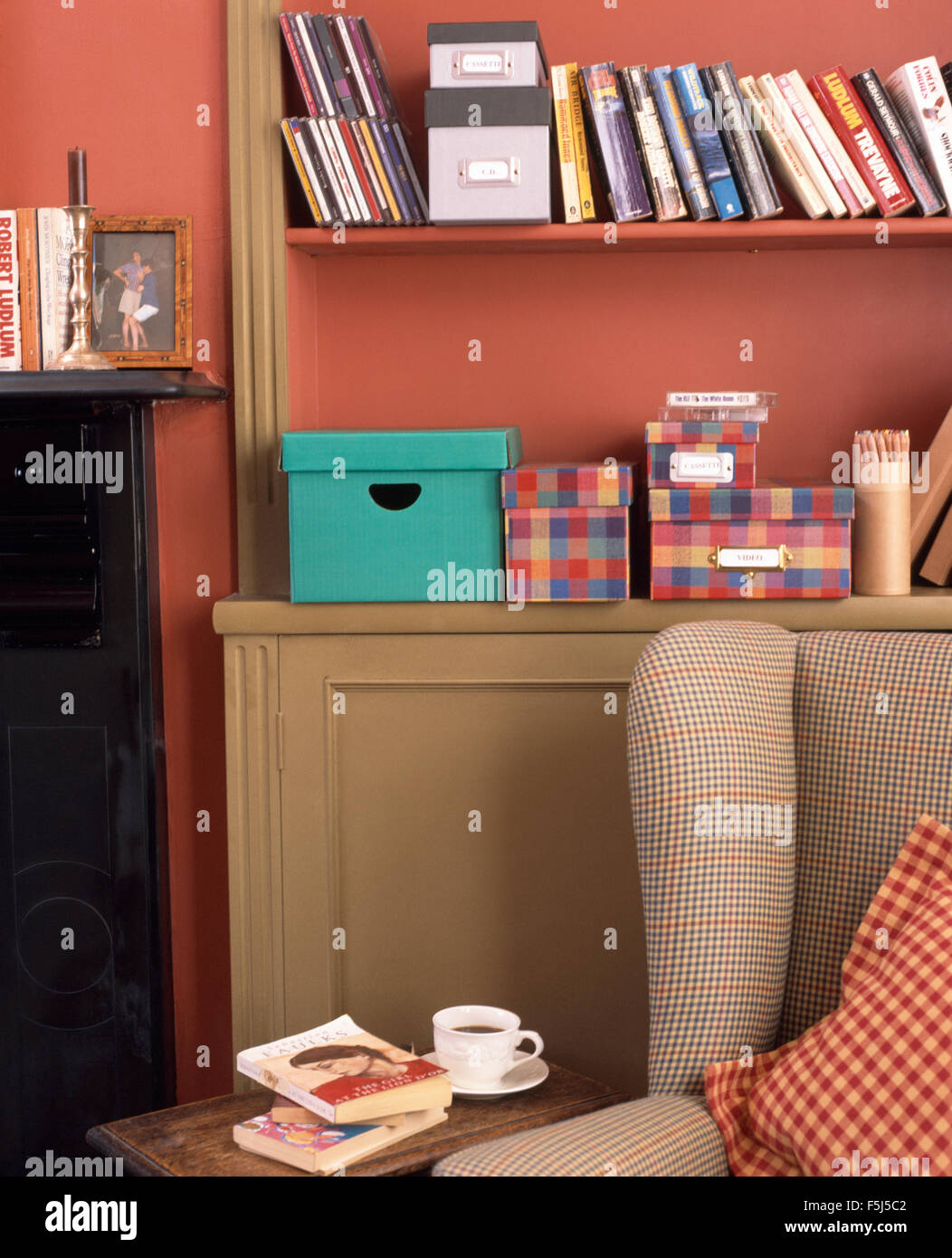 Books and storage boxes on shelves in red economy nineties living room ...